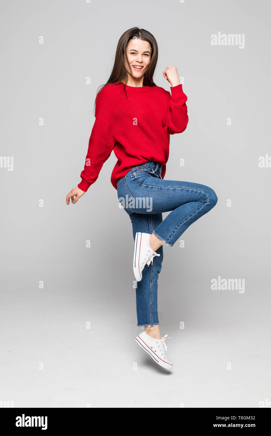 Full length portrait of a laughing woman jumping over gray background ...