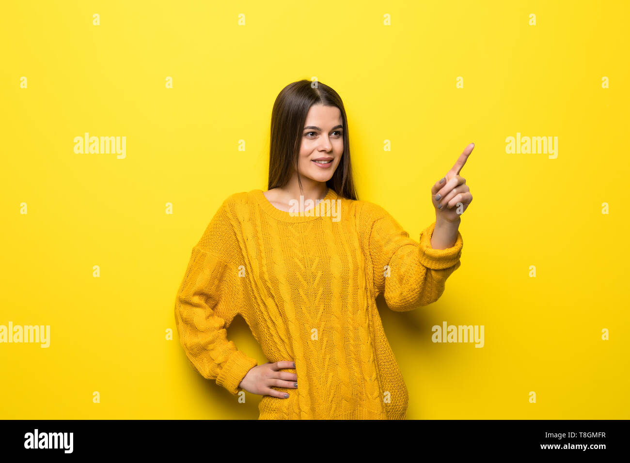 Young woman pointed side wearing in yellow sweater isolated on yellow ...