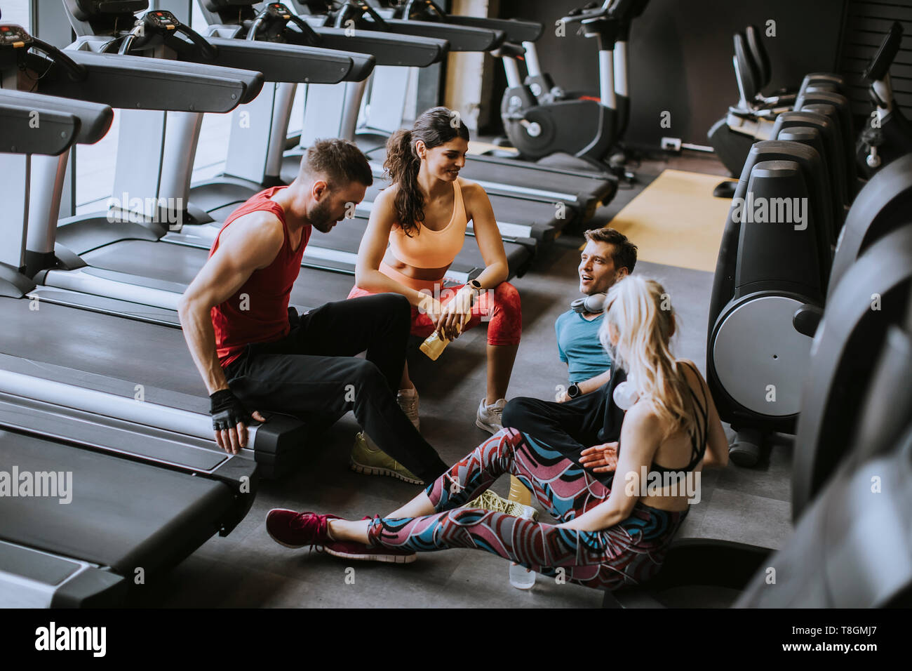 Group of young people in sportswear talking and laughing together while ...