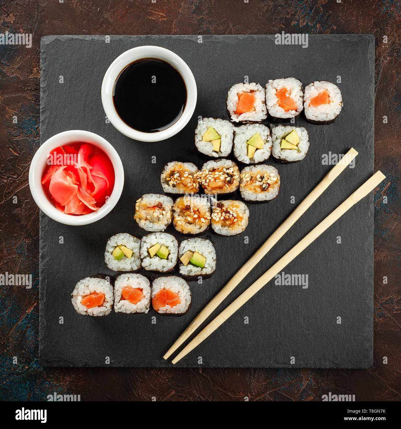 Japanese sushi rolls served on stone slate on dark background. Sushi ...