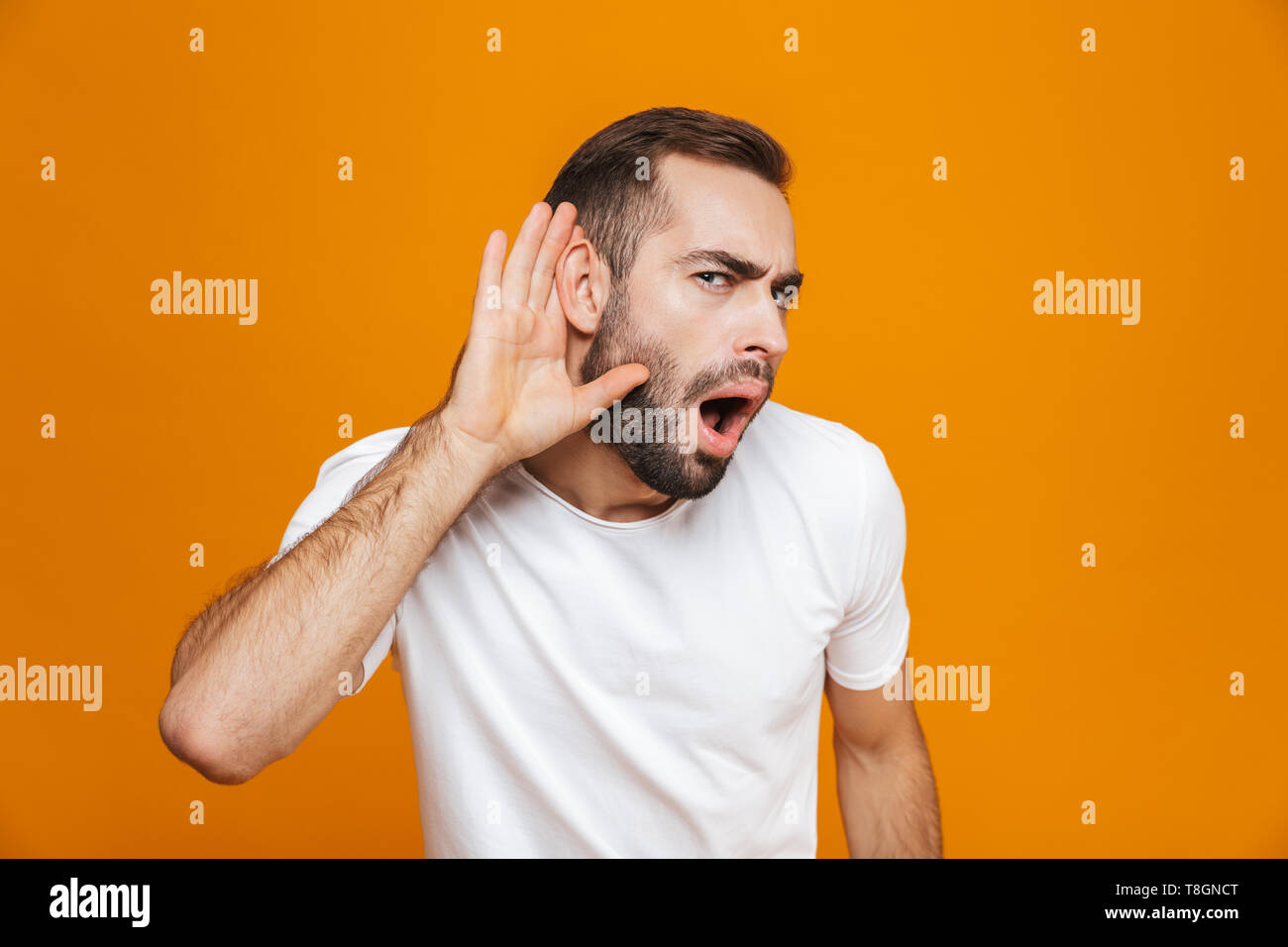 Image of european man 30s trying to hear something while keeping hand ...