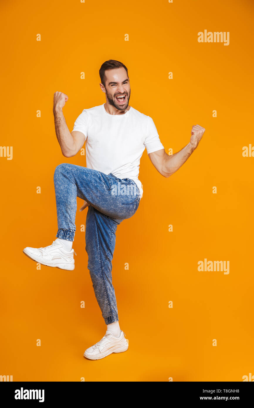 Full length image of ecstatic guy 30s in t-shirt and jeans laughing and ...