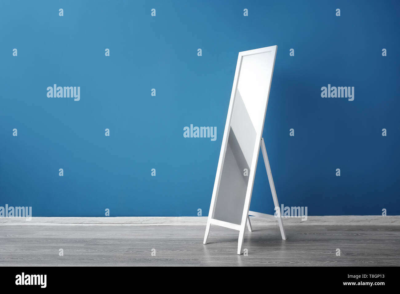 Big stylish mirror near color wall in empty room Stock Photo - Alamy