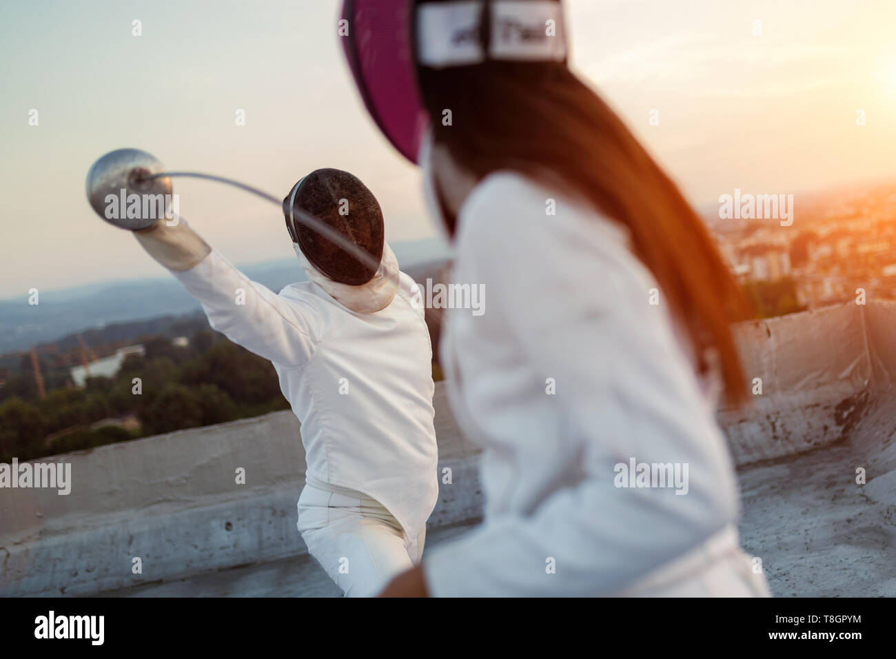 Two fencing athletes people fight on rooftop outdoors Stock Photo - Alamy