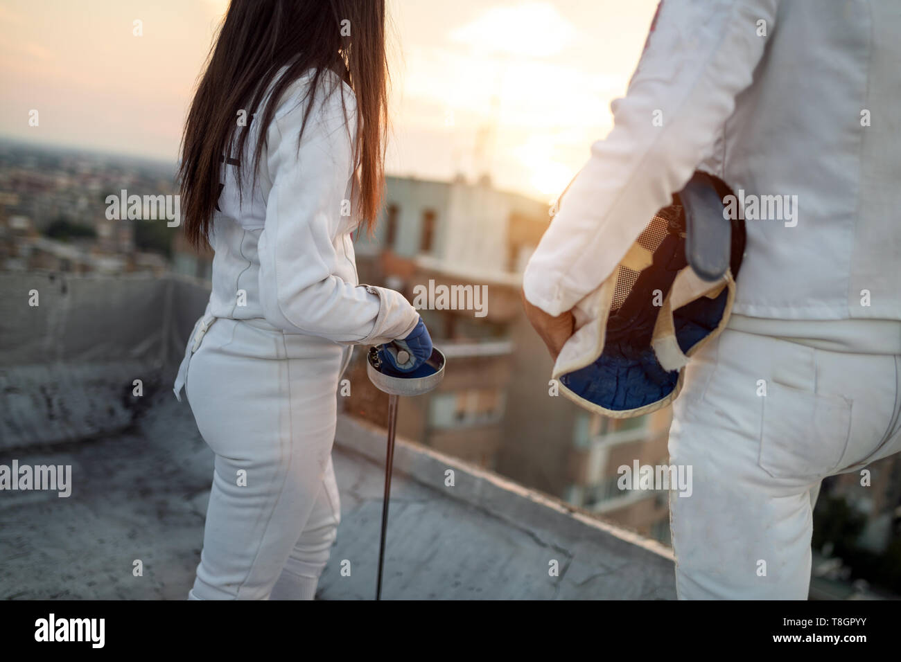 Two fencing athletes people fight on rooftop outdoors Stock Photo - Alamy