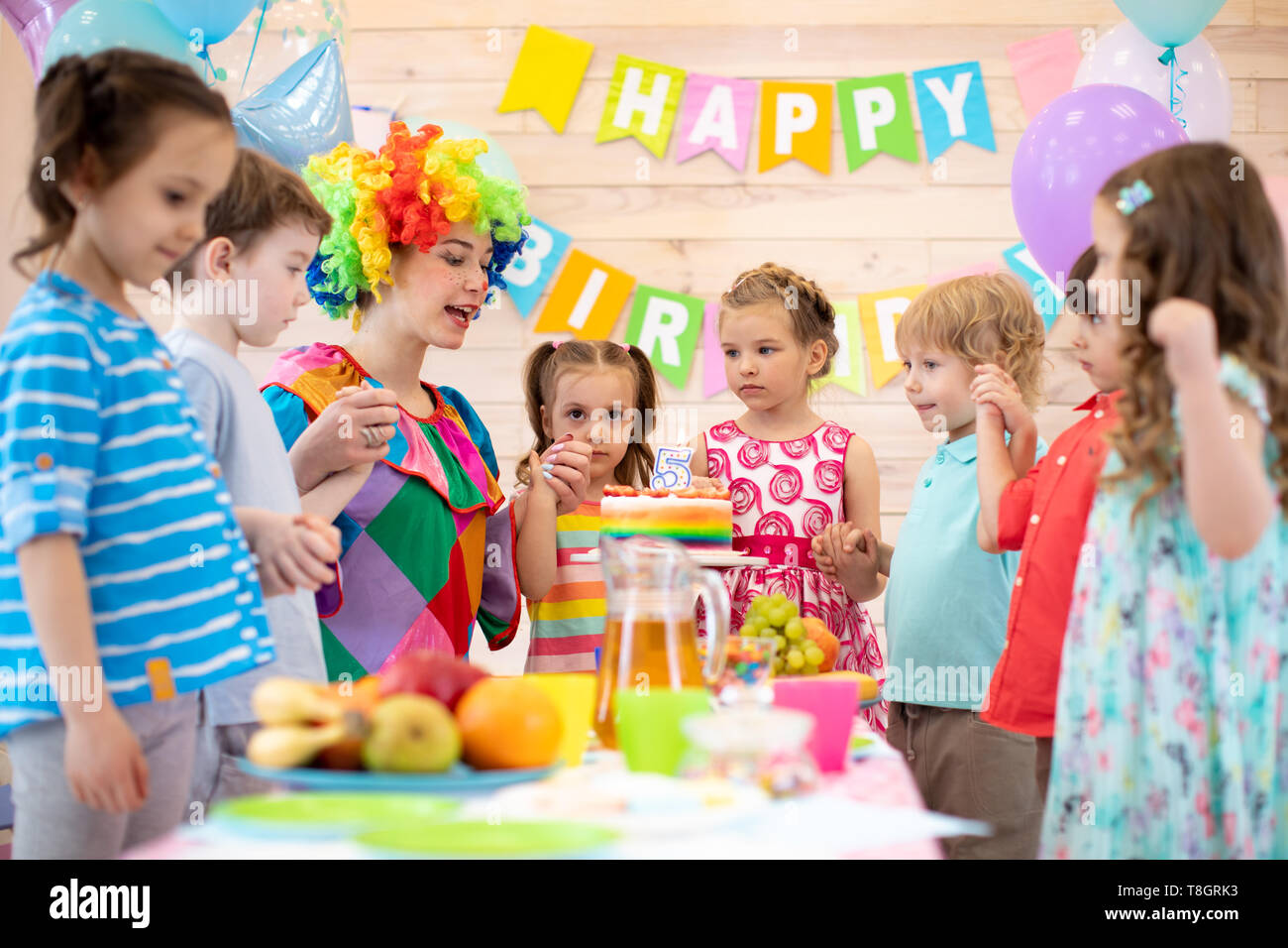 Children group with clown celebrating birthday party in daycare. Happy ...