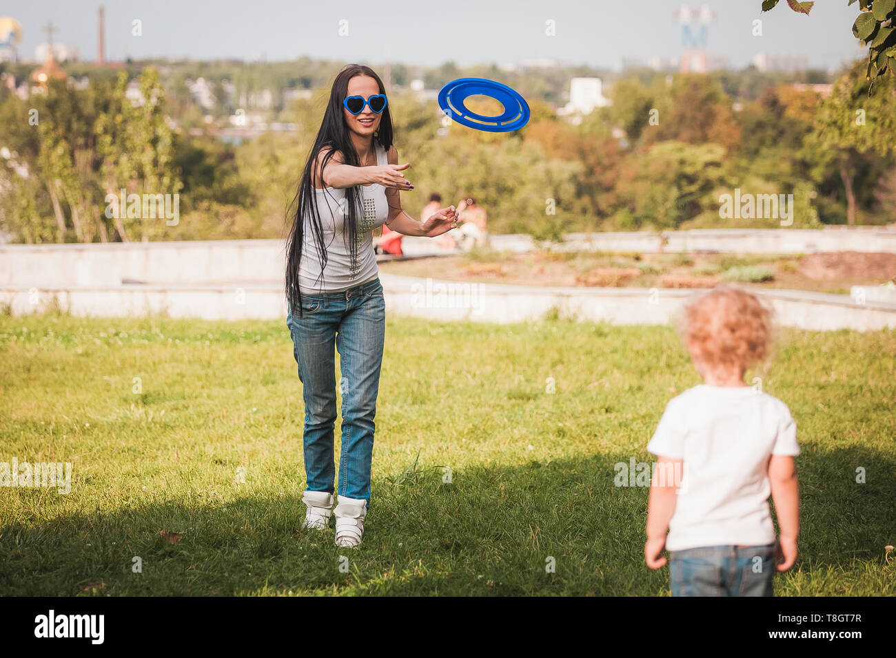 Family playing frisbee on meadow in park, summer day. Mom throwing ...