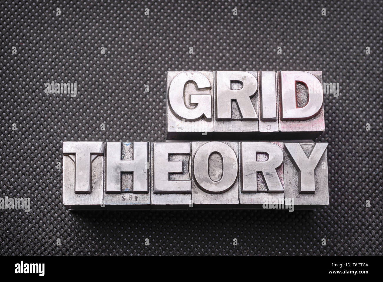 grid theory phrase made from metallic letterpress blocks on black ...
