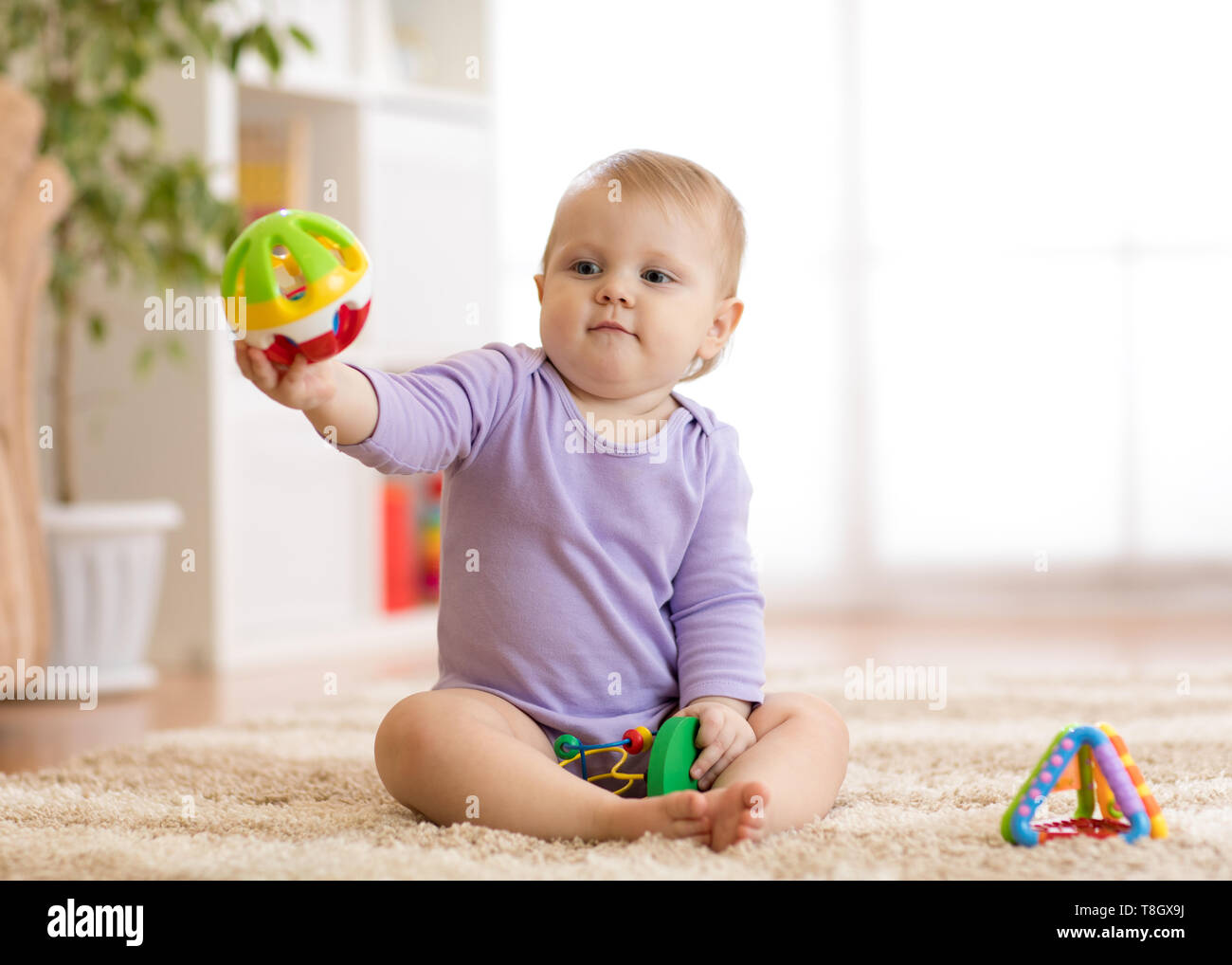 Baby playing on rug on the floor in nursery Stock Photo - Alamy