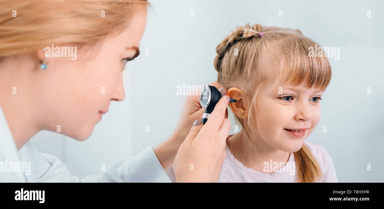 audiologist examining little patient with otoscope, hearing exam of ...