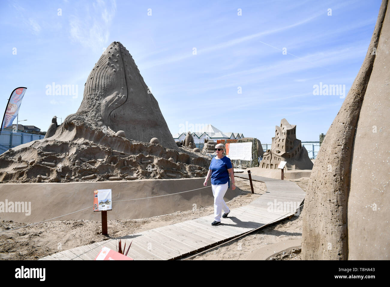 A woman walks past a huge sculpture of a blue whale surrounded by ...