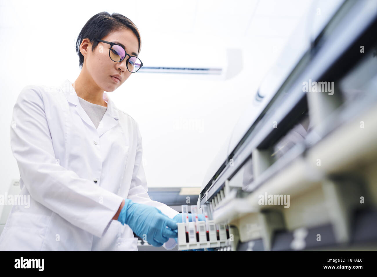 Asian laboratory employee placing blood samples into machine Stock ...