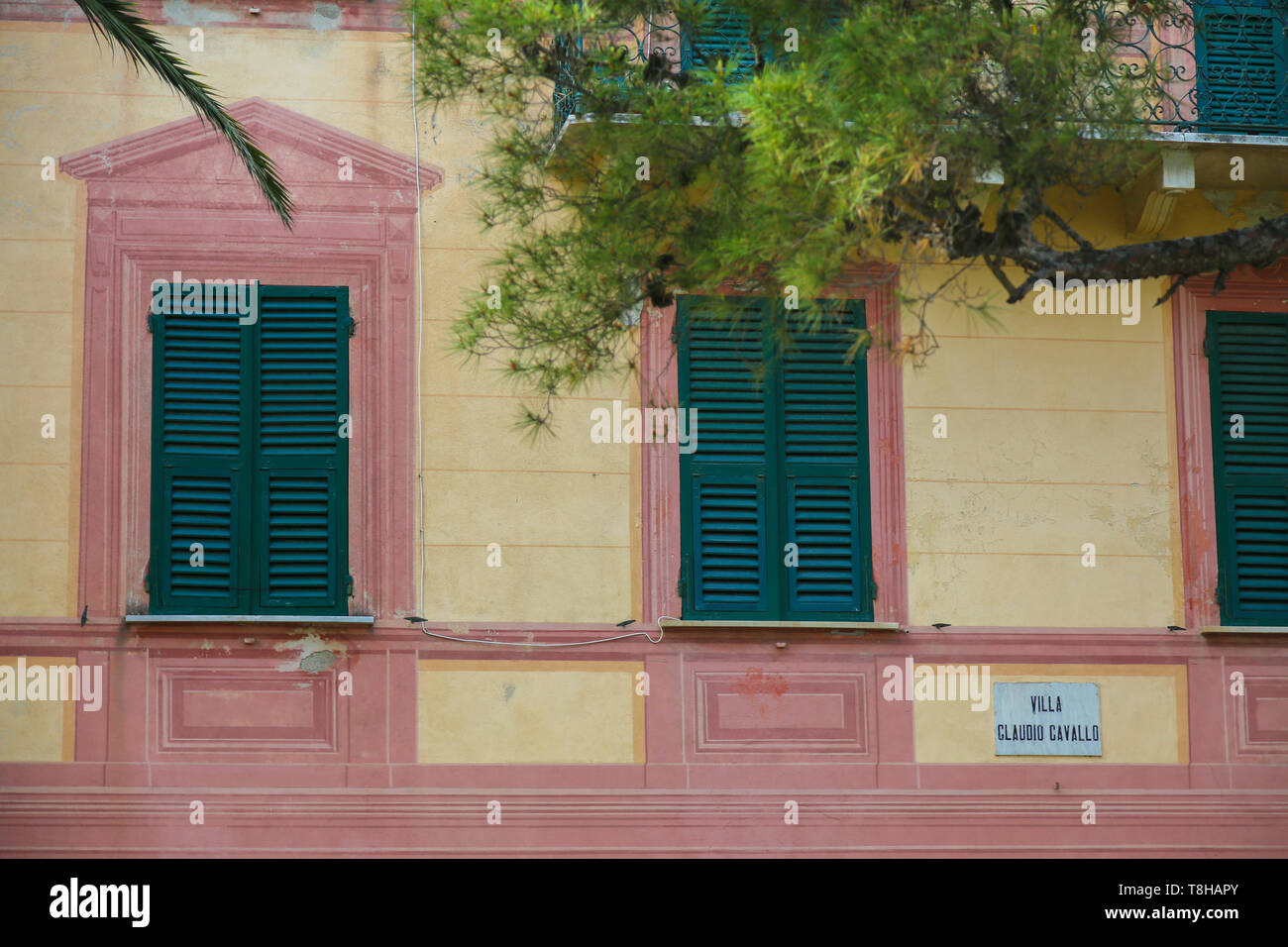 Part of the facade of an Yellow and pink italian building with windows ...