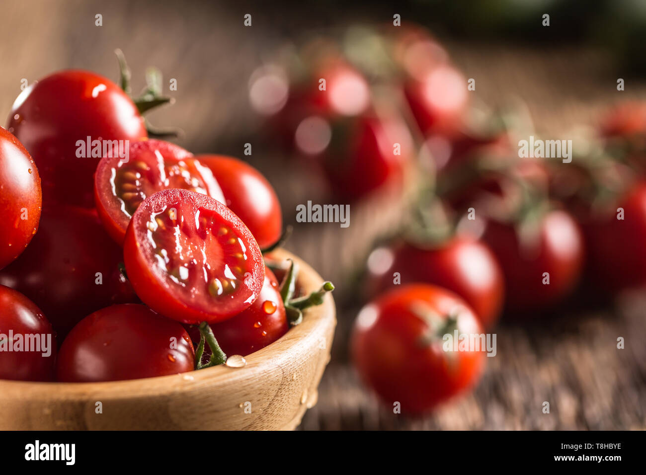 Fresh cherry tomatoes in wooden bowl on old oak table Stock Photo - Alamy
