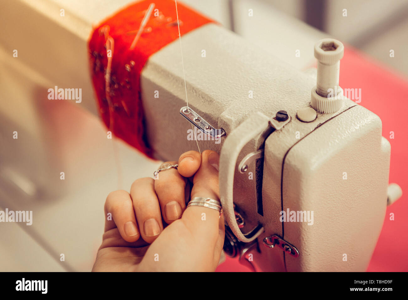 Hand of a tailoress inserting thread into the sewing machine Stock ...