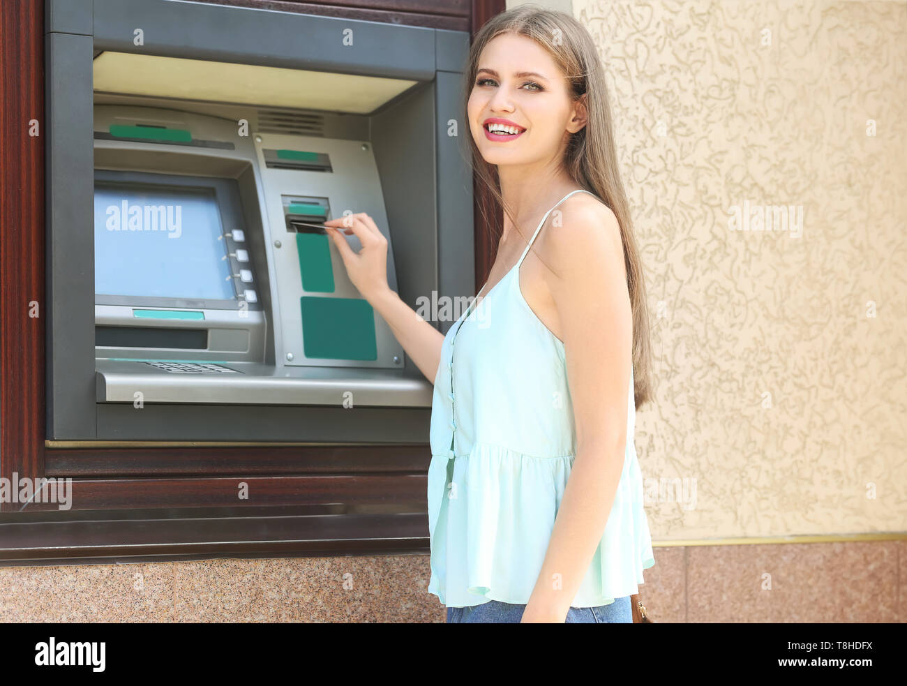 Woman inserting credit card into cash machine outdoors Stock Photo - Alamy