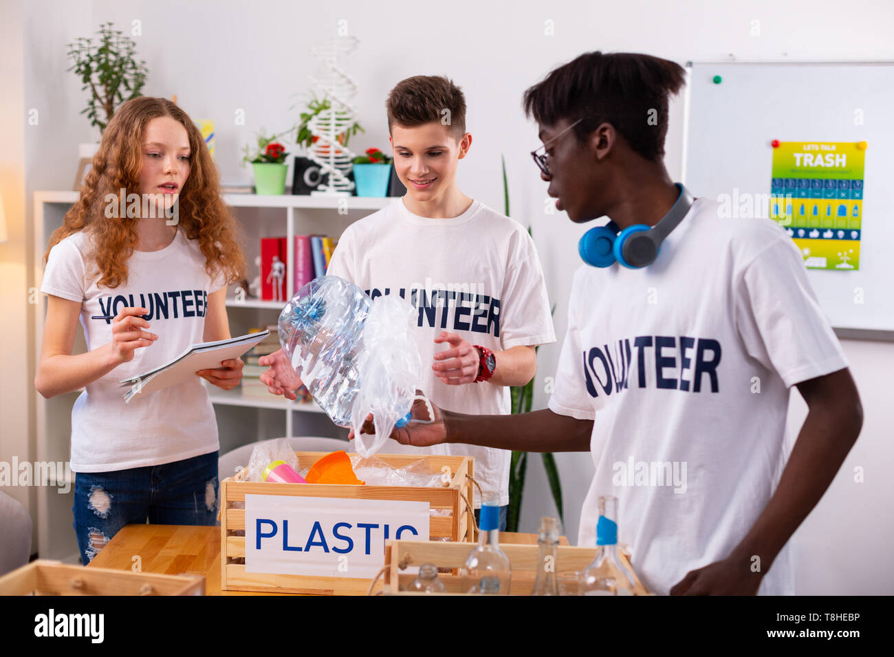 Dark-skinned teenager giving bottle to friend while sorting waste Stock ...
