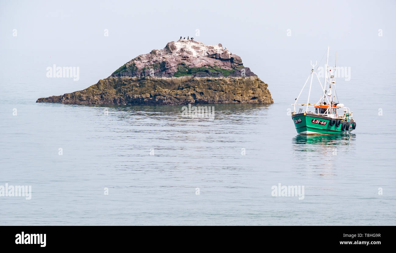 Dunbar fishing boat in calm sea next to small rocky island with ...