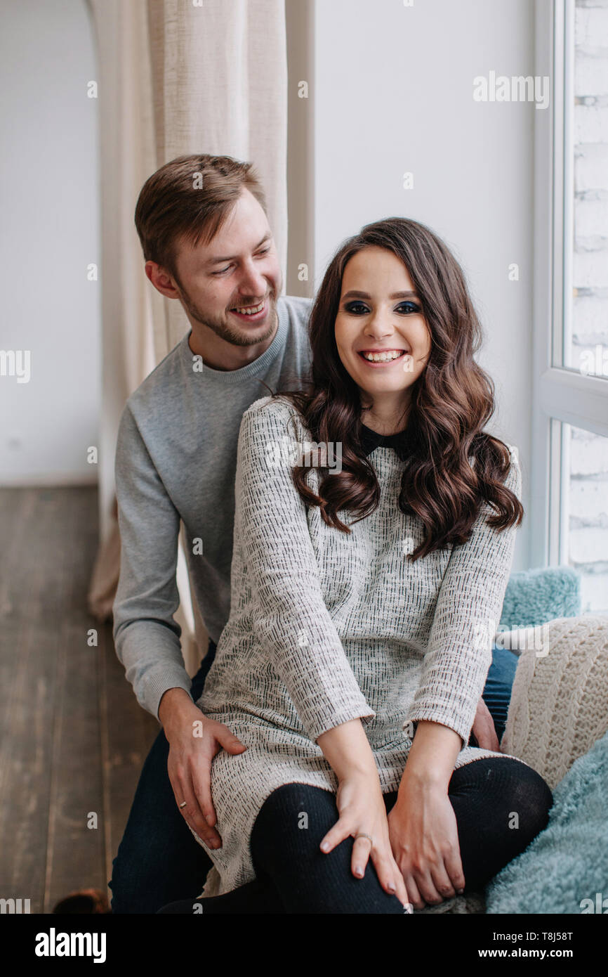 Smiling couple sitting by a window Stock Photo - Alamy