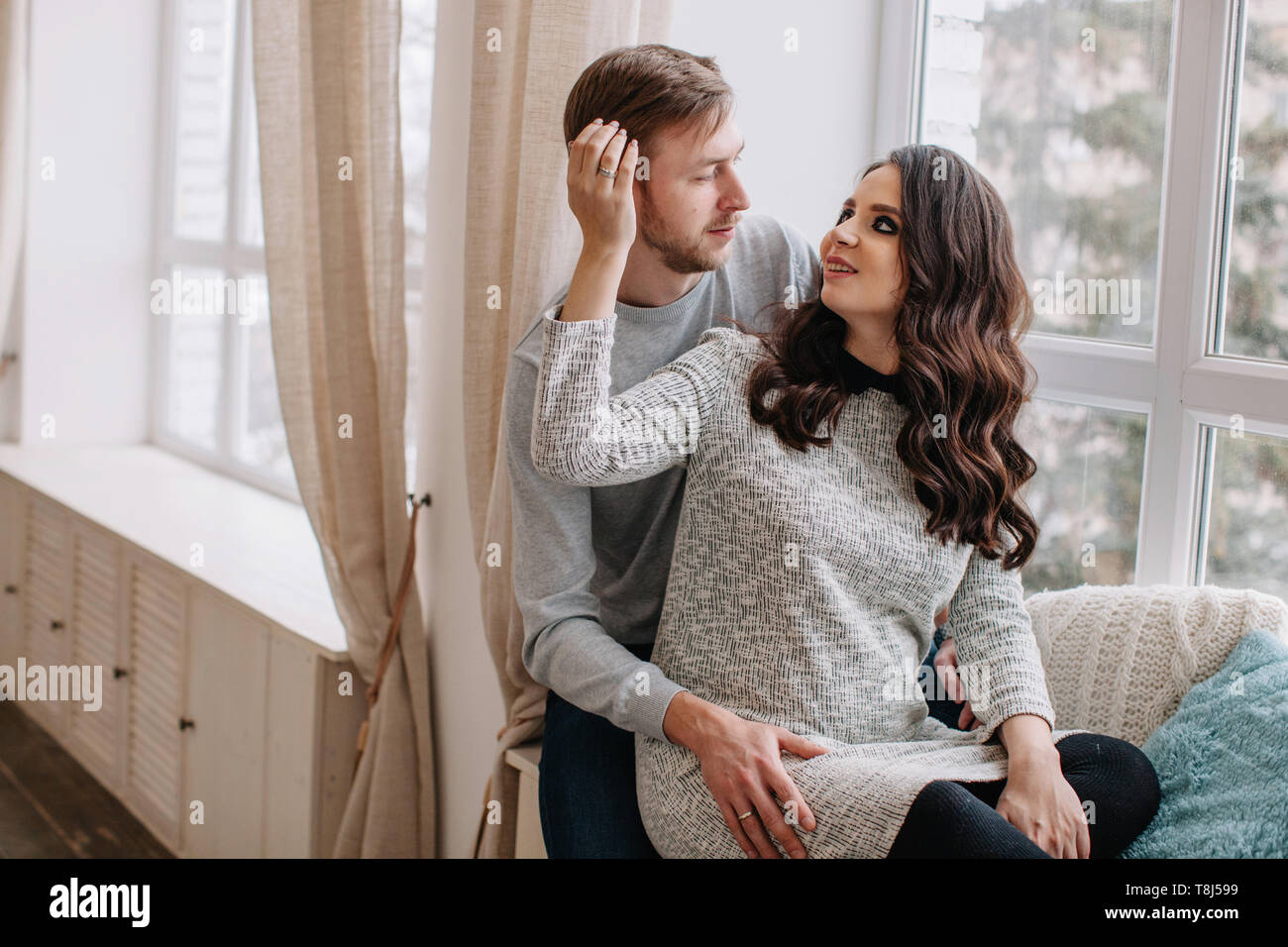 Smiling couple sitting by a window Stock Photo - Alamy