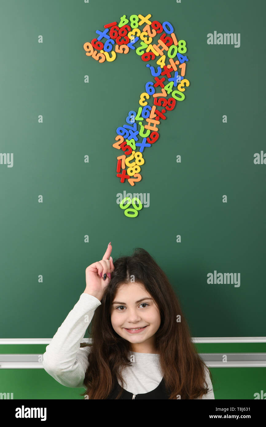 Smiling little schoolgirl on green school board. A magnetic question ...