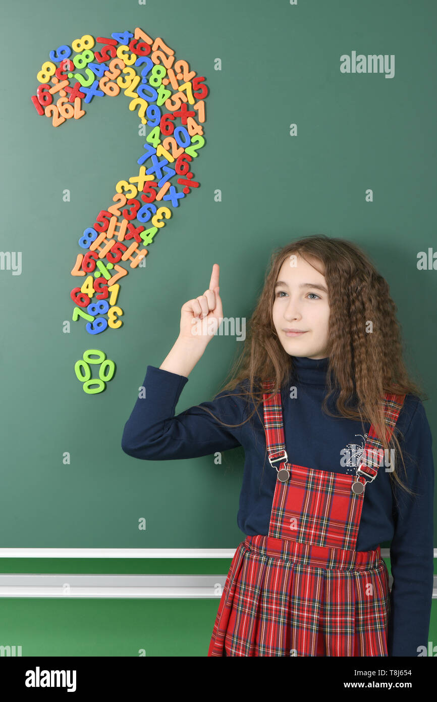 Smiling little schoolgirl on green school board. A magnetic question ...