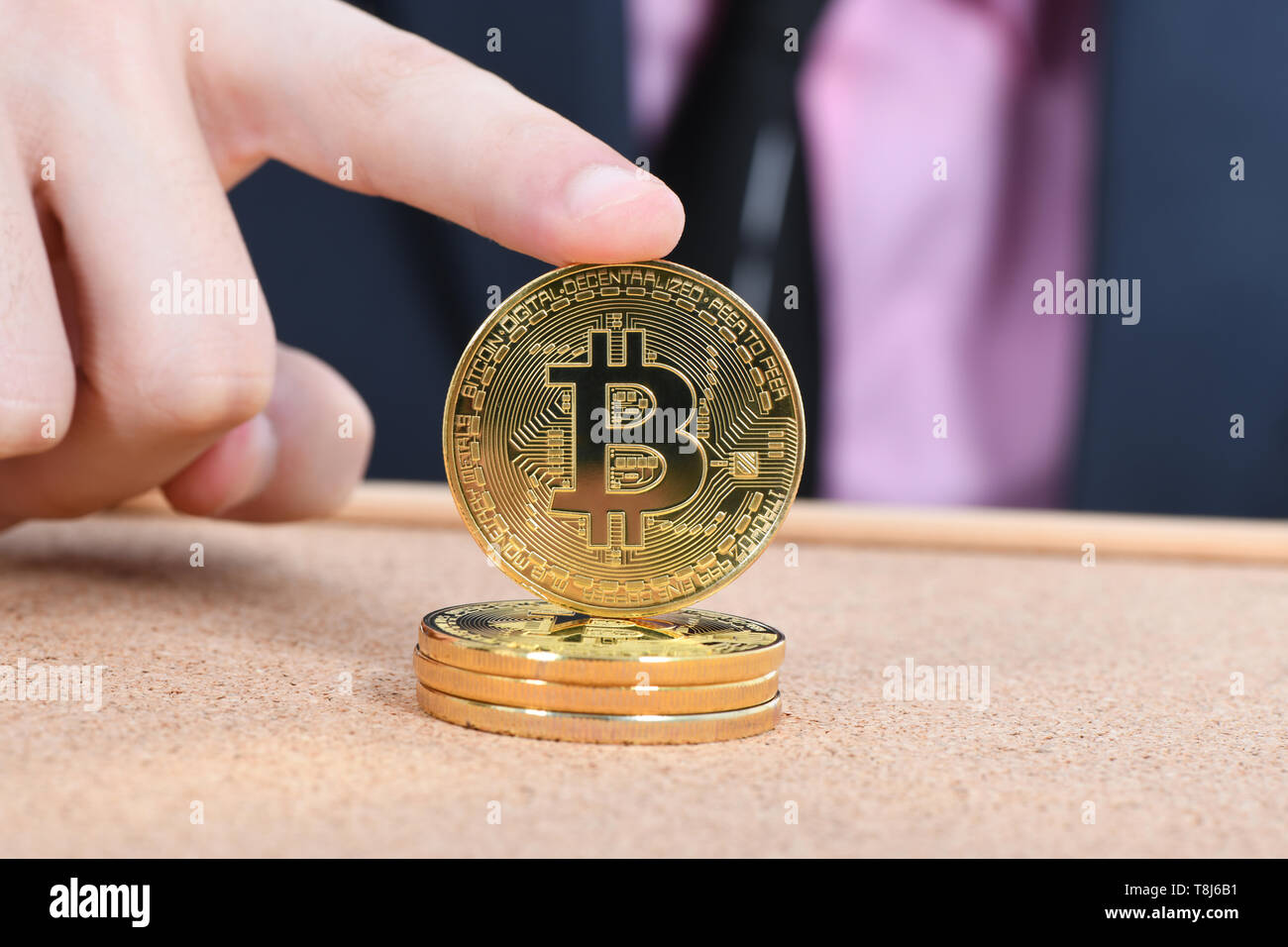 Man's hand holding golden Bitcoin on brown textured cork background ...