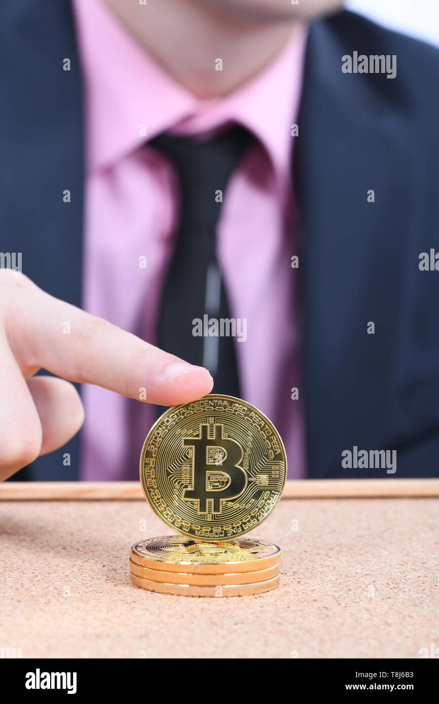 Man's hand holding golden Bitcoin on brown textured cork background ...