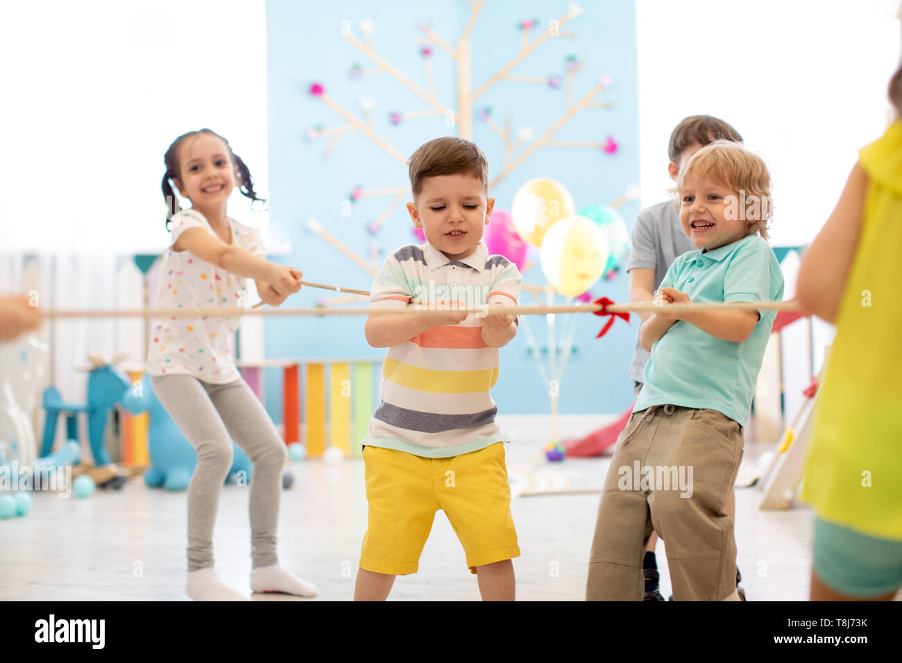 group of preschool kids play and pull rope together in daycare Stock ...
