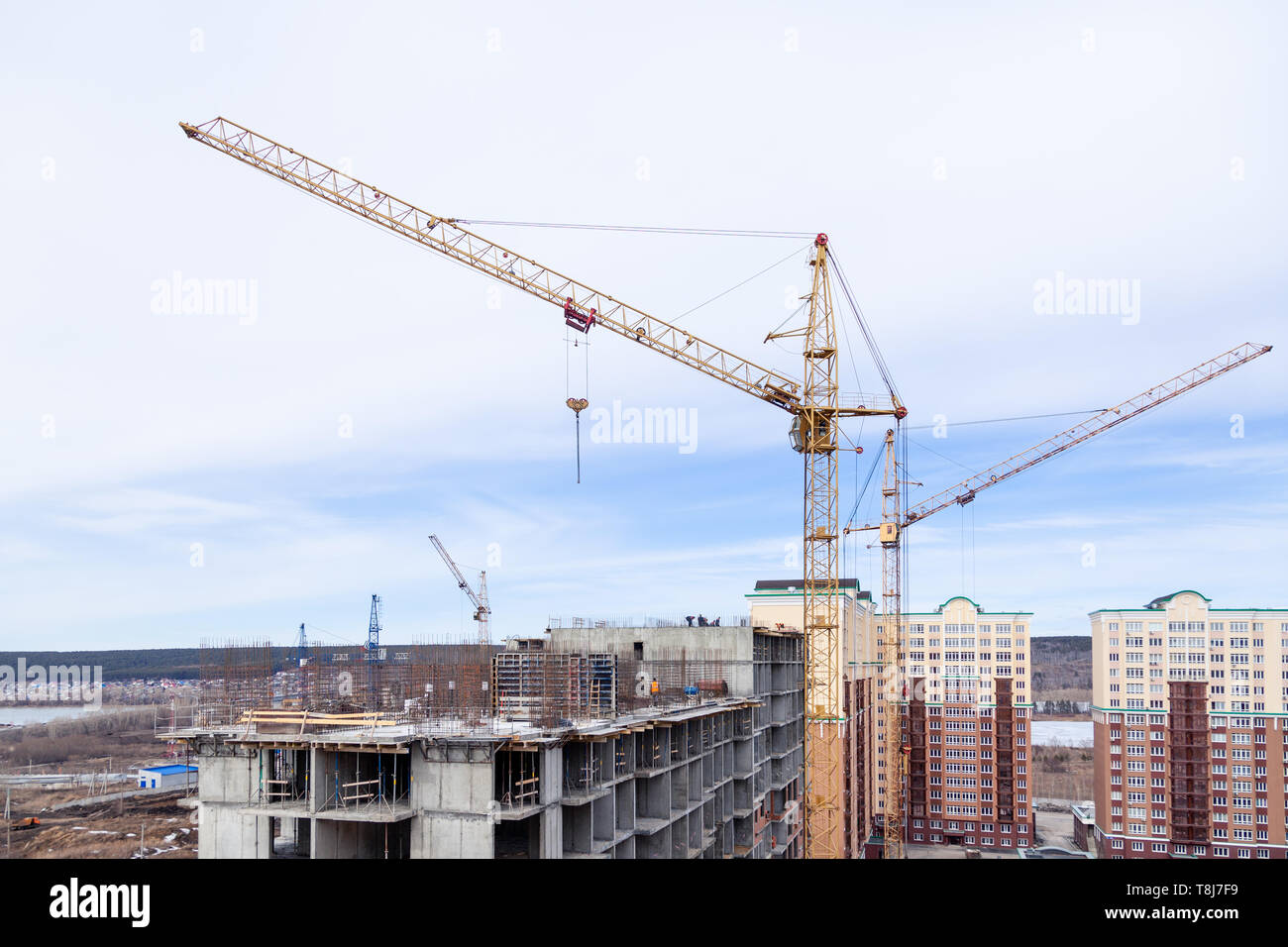 High-rise mighty hoisting crane and large building construction site ...