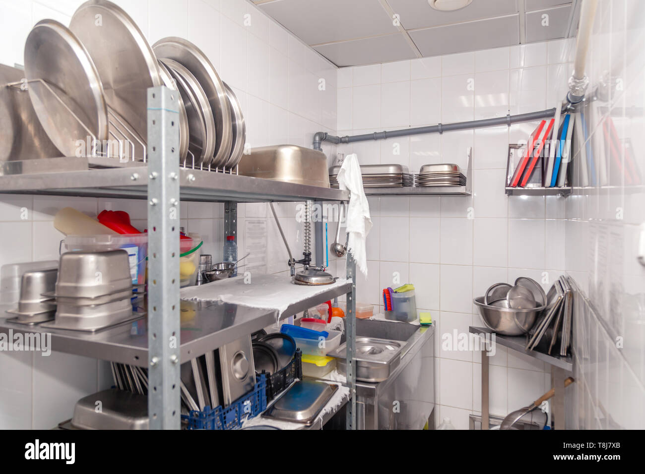 View of restaurant's professional washer, sink, brushes, metal shelving ...