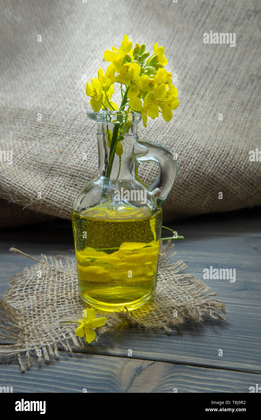 Yellow canola or rapeseed flowers with a small glass decanter of oil on ...