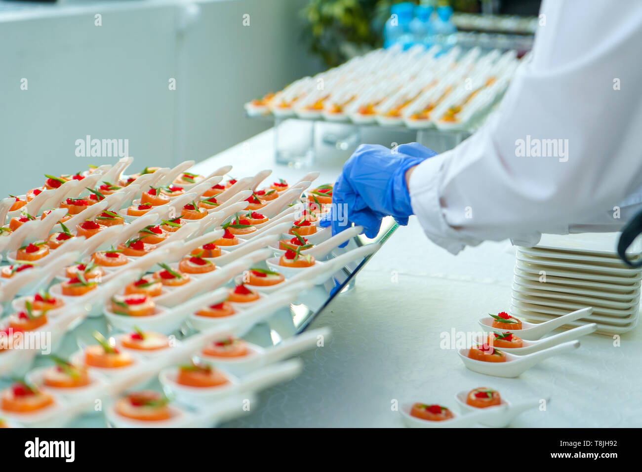 Gloved hands, waiter, serves a catering of small canapes of red fish ...