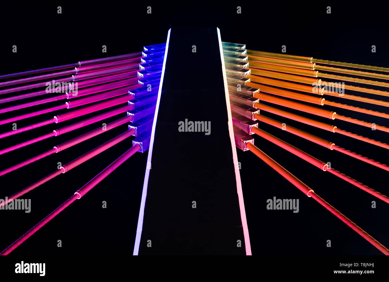 Abstract closeup of multi coloured lit cables attaching to a pylon ...