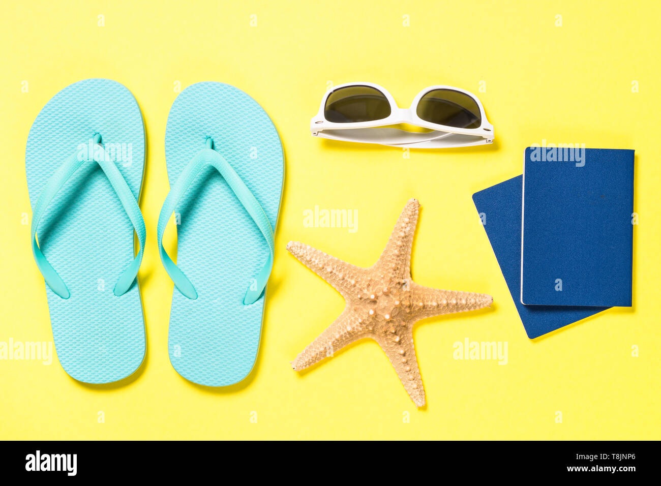 Blue flip flops, sunglasses, passport and starfish on yellow Stock ...