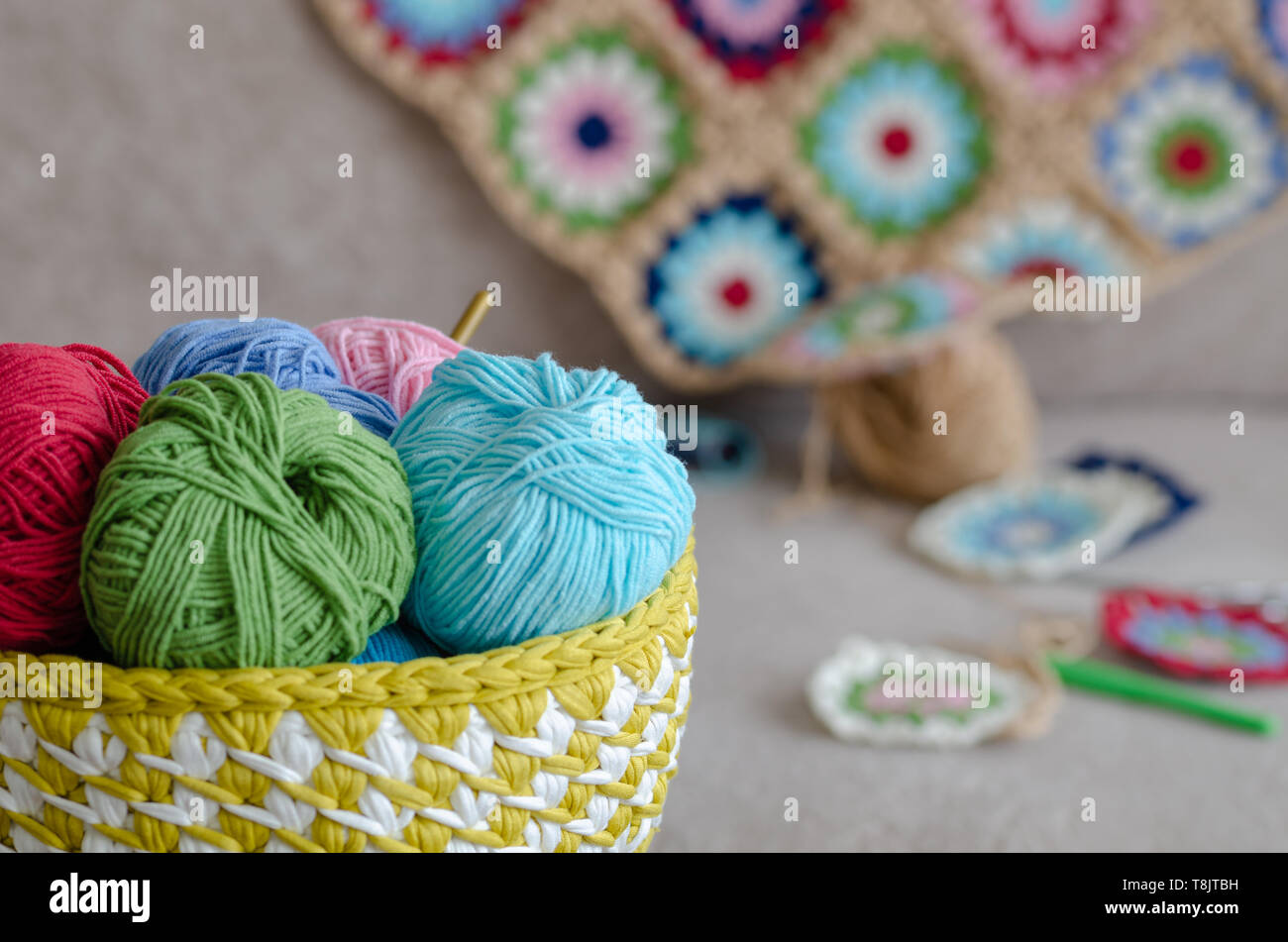 Multi Colored baby blanket and colorful yarns on sofa. Green, pink ...