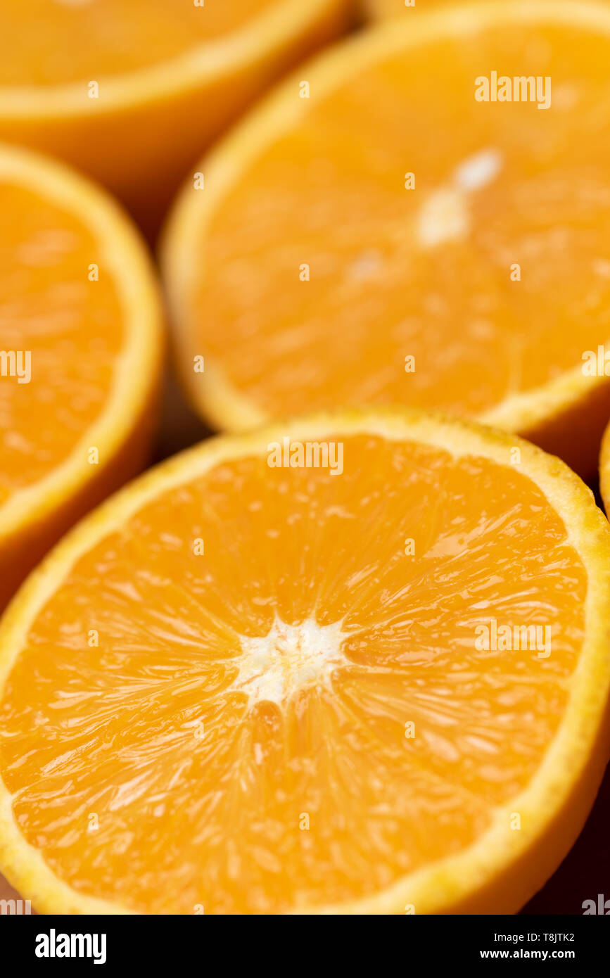 Orange background. Closeup of half cut fruits in pattern next to each ...