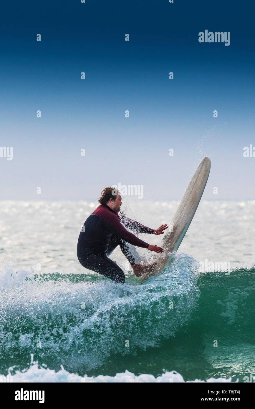 A surfer riding a surfboard on the crest of a wave at Fistral in ...