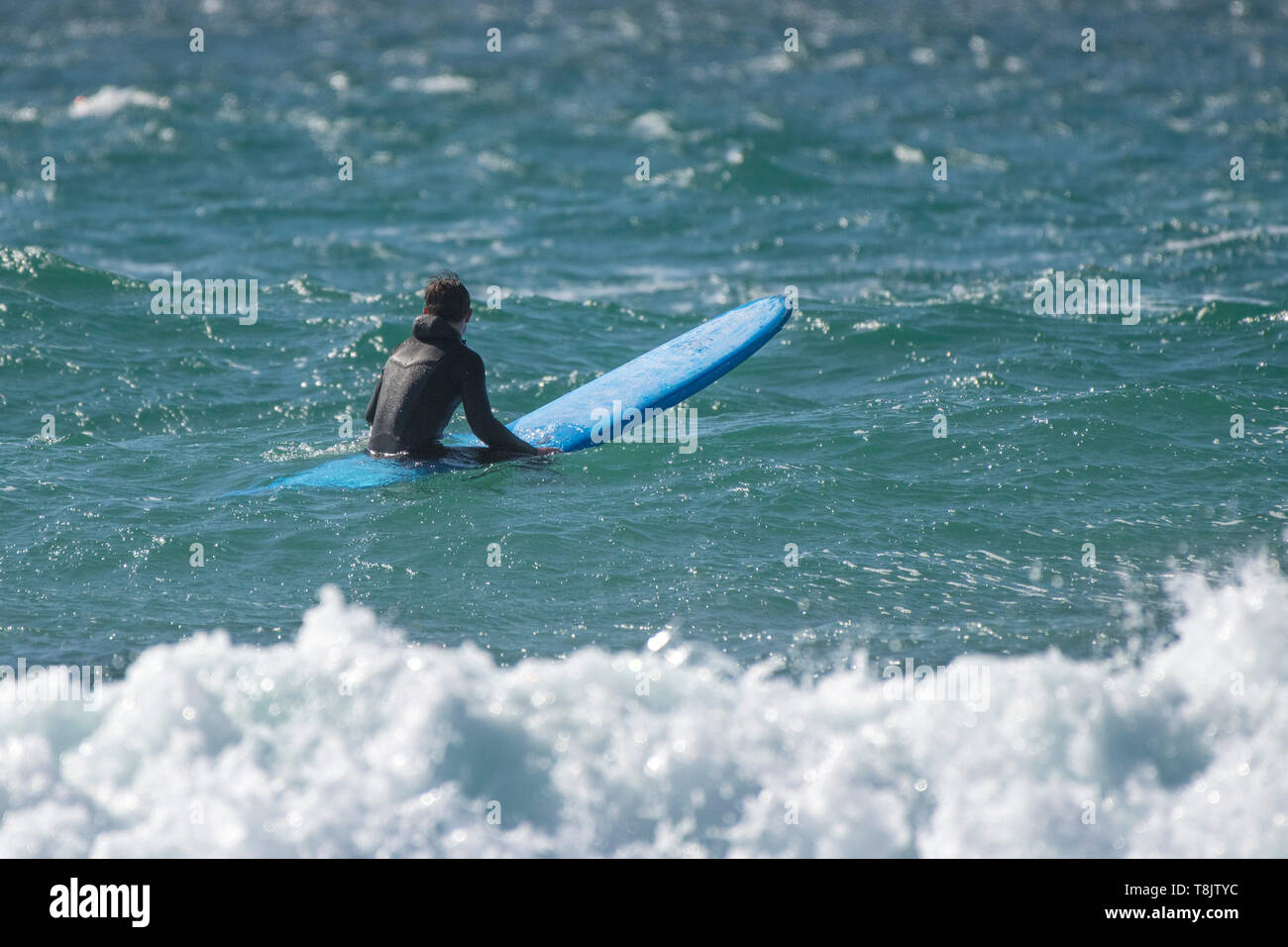 A surfer sitting on his surfboard waiting for a wave Stock Photo - Alamy
