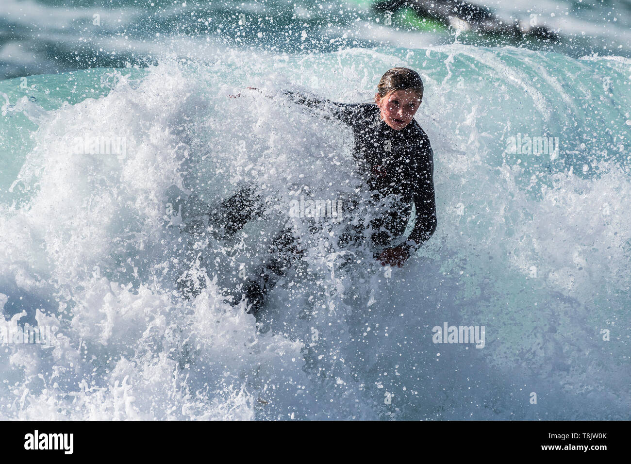 Spectacular surfing action as a young female surfer is covered in spray ...