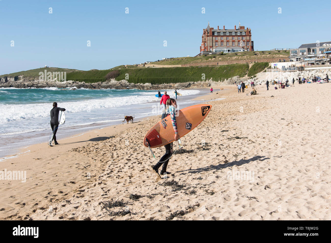 Surfers carrying their surfboards walking across Fistral Beach in ...