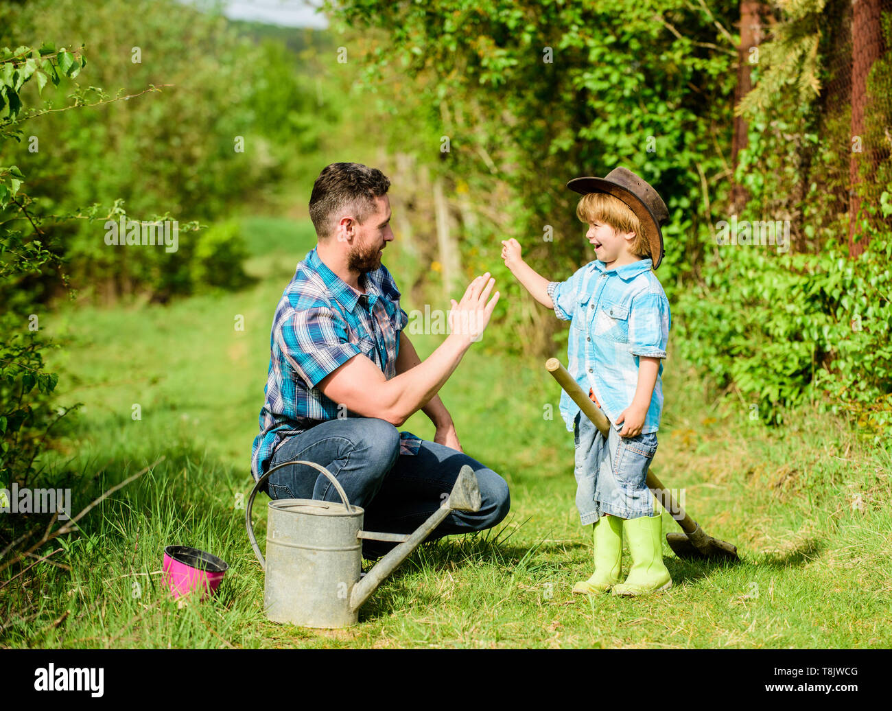 small boy child help father in farming. use watering can and pot ...