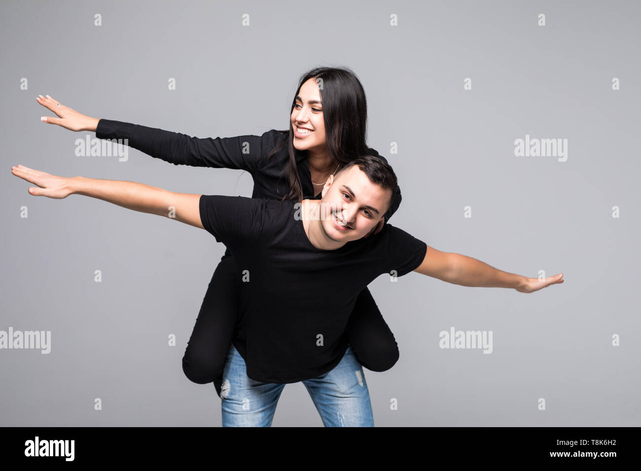 Young couple with hands arms like wings piggy-back ride walk highway ...