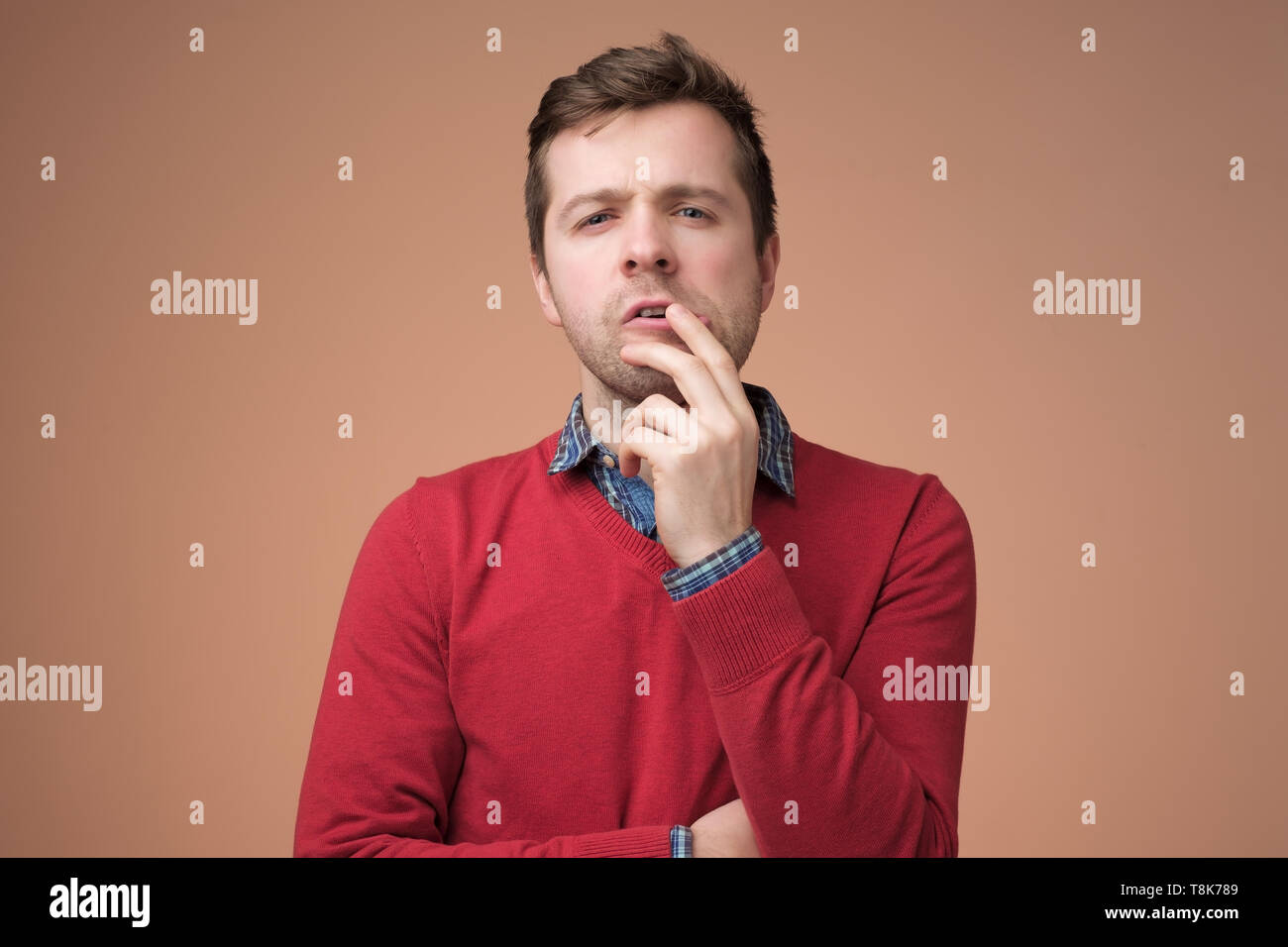 Young man in red sweater trying to make a choice Stock Photo - Alamy