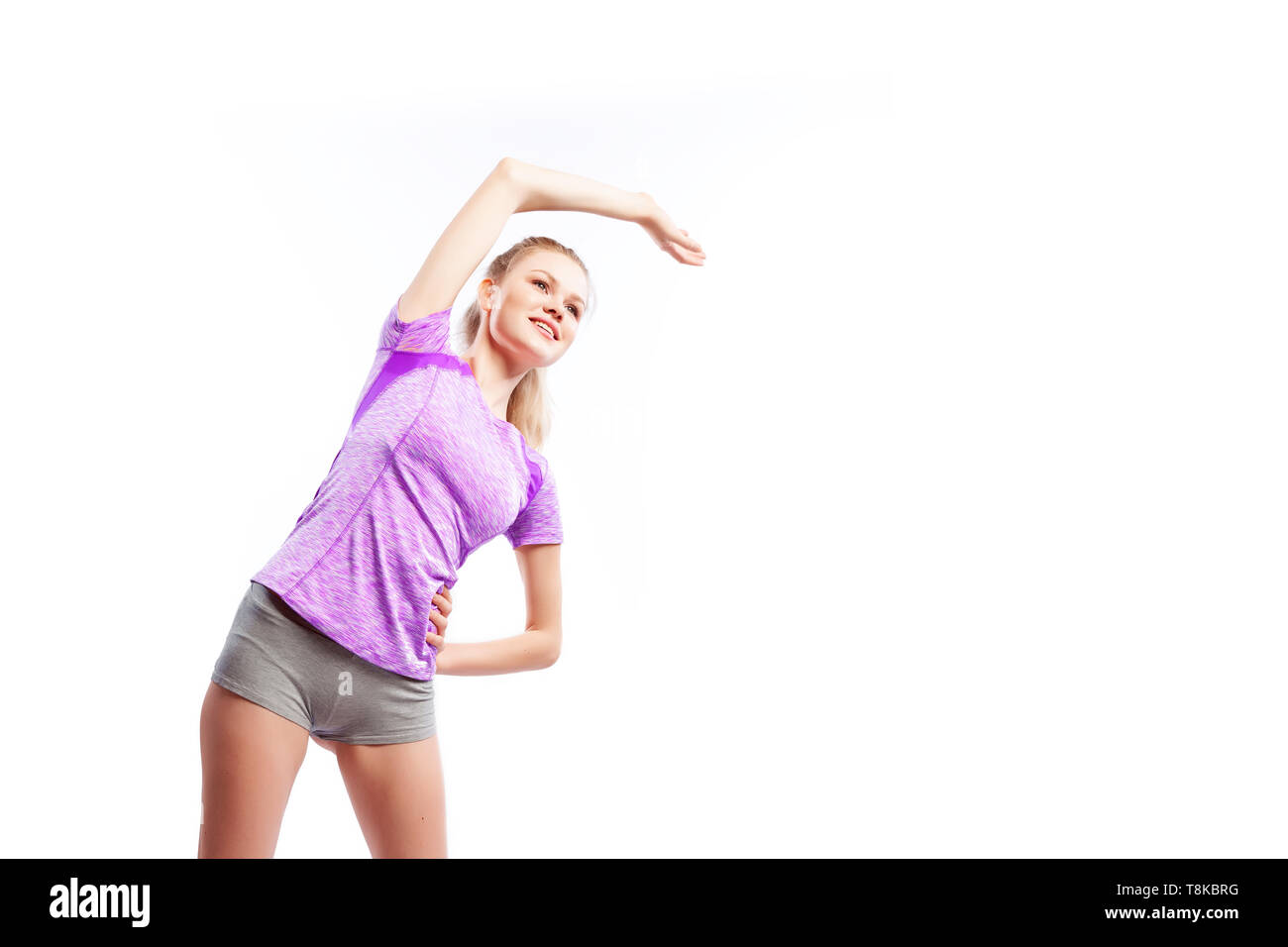 Young woman in sports clothes doing side bends on white isolated ...