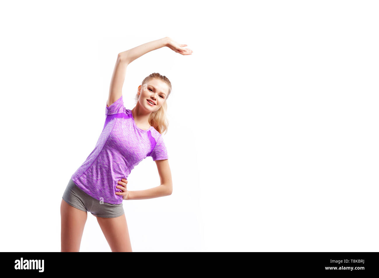 Young woman in sports clothes doing side bends on white isolated ...