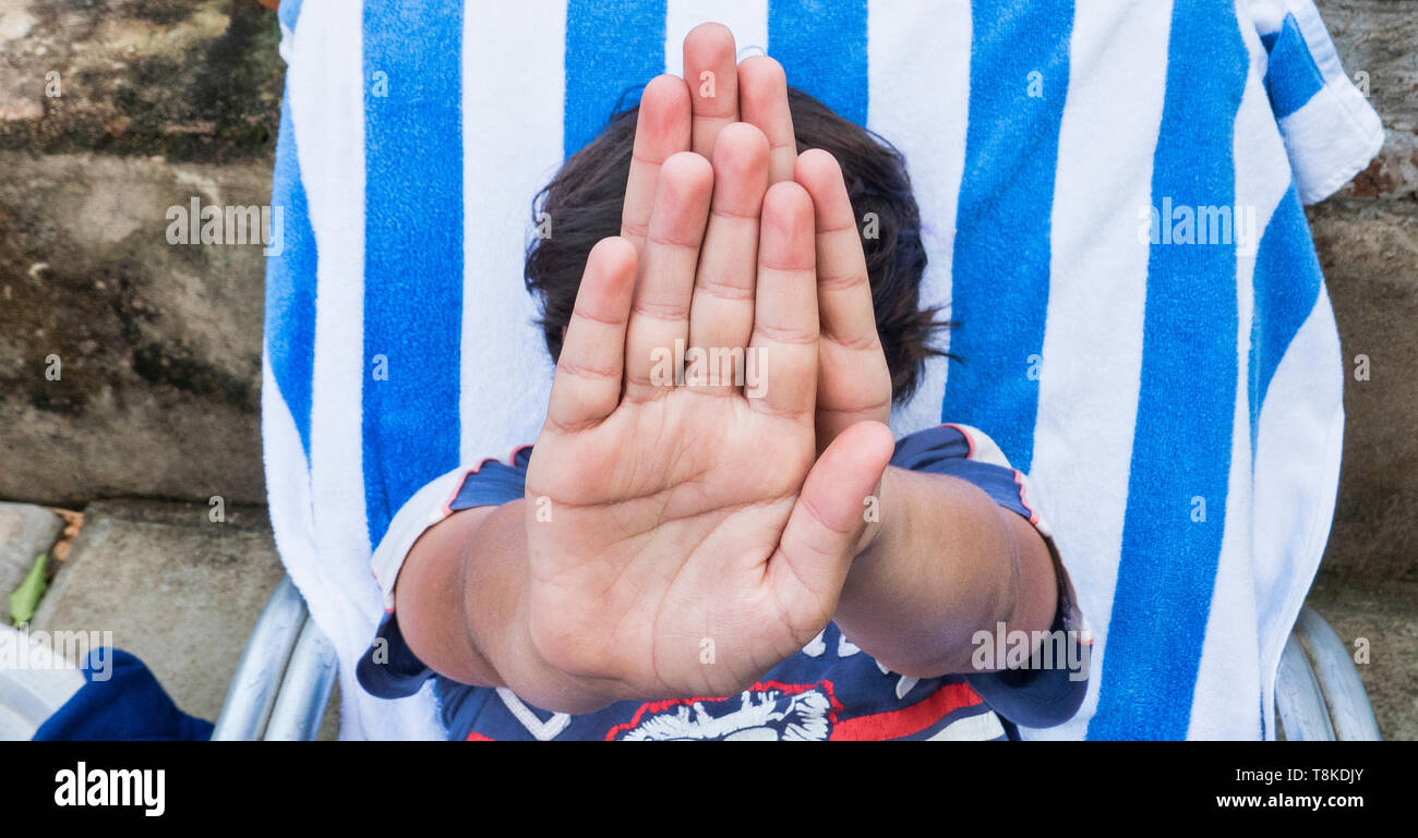 a teen boy upset, covers his face with his hands. close-up of face and ...
