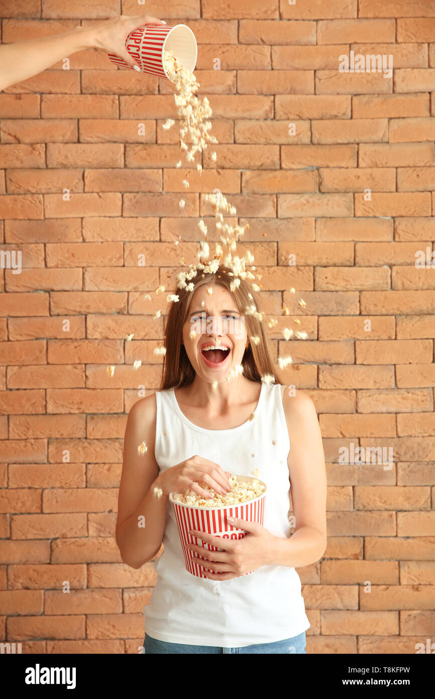 Popcorn falling onto beautiful young woman against brick wall Stock ...