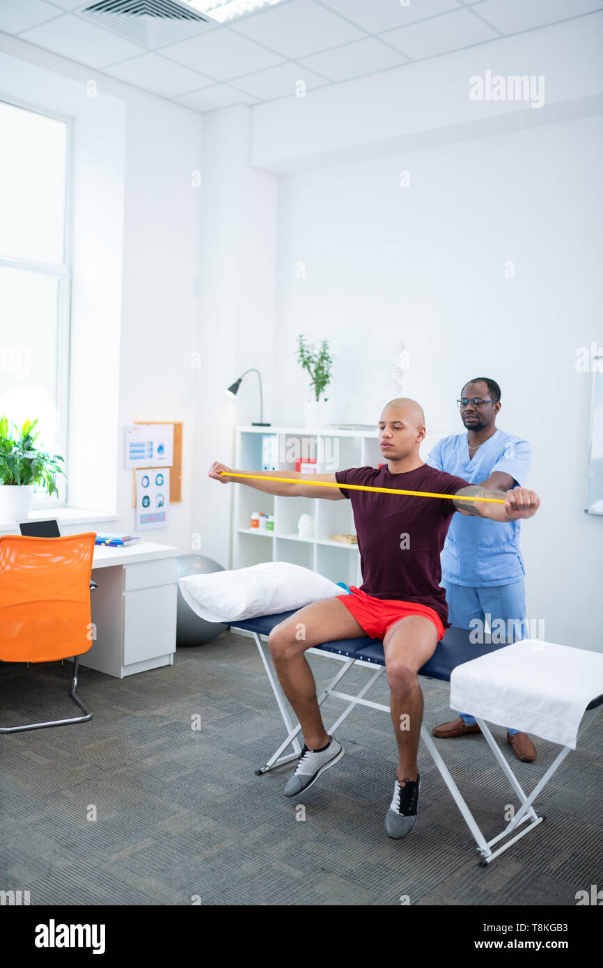 Bodybuilder stretching his arms while visiting sports therapist Stock ...