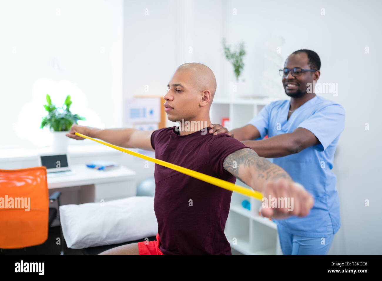 Sportsman holding ribbon stretching arms visiting therapist Stock Photo ...